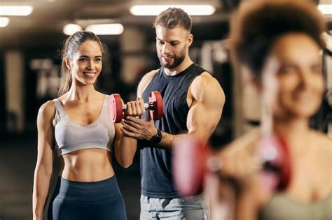 Premium Photo Selective Focus On A Sportswoman Doing Dumbbells Curls While Coach Helping Her