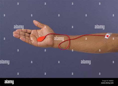 Arm Of Biracial Man With Heart Sticking Plaster And Red String With