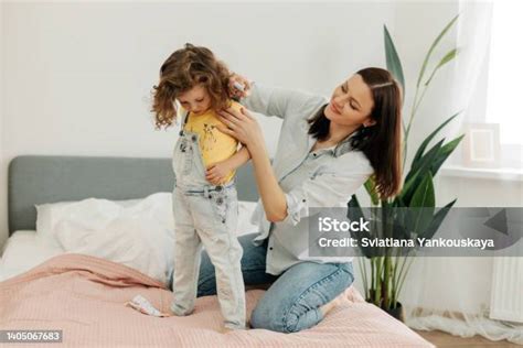 젊은 어머니는 어린 딸이 옷을 갈아 입도록 도와줍니다 자녀 돌보기 도움 모성 의류에 대한 스톡 사진 및 기타 이미지 의류 드레스 딸 Istock