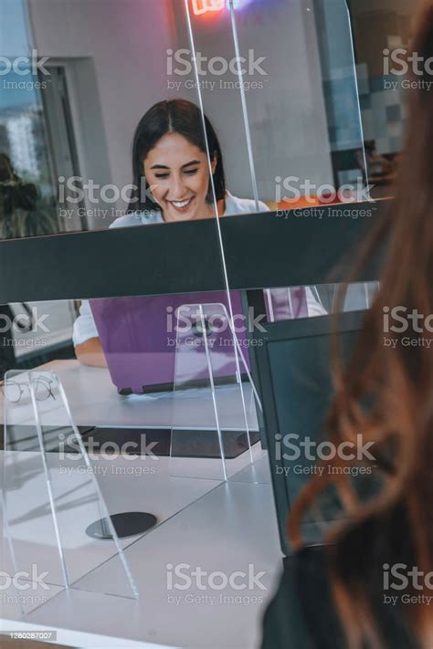 전염병 동안 현대 사무실에서 아크릴 유리 재채기 벽 가드 뒤에 일하는 젊은 비즈니스 여성 투명 아크릴 유리에 대한 스톡 사진 및 기타 이미지 투명 아크릴 유리 25