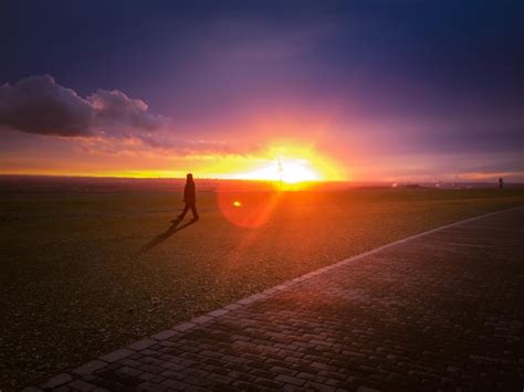 Silhouette Person Walking On Field During Sunset Premium Photo