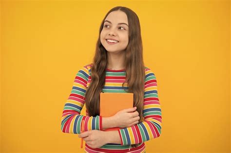 十代の少女の生徒は、黄色の背景のコピースペースに分離された本のノートブックを保持します学校に戻る十代のライフスタイルの教育と知識 プレミアム写真