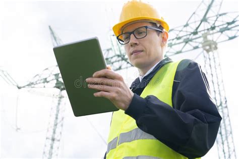 Engineer With Digital Tablet On A Background Of Power Line Tower Stock