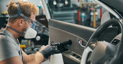 인공 호흡기 마스크를 쓴 남자는 고압 총 근접 촬영으로 스티어링 휠의 화학 청소를 수행합니다 사진 Unsplash의 청소 이미지