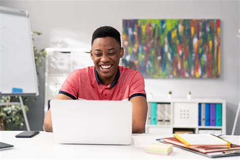 어린 나이의 잘 생긴 소년은 방 사무실 그 옆에 노트북 앞 책상에 앉아 그 옆에 전화및 노트북 교사는 웹캠을 통해 학생 이야기 원격 교육 온라인 학교 가정의 방에 대한 스톡