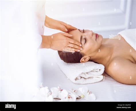 Beautiful Brunette Woman Enjoying Facial Massage With Closed Eyes In
