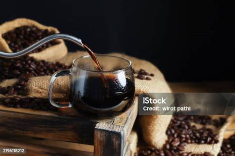 뜨거운 커피를 커피 컵에 붓고 볶은 커피 콩을 검은 색과 어두운 배경의 테이블에 배치합니다 갈색에 대한 스톡 사진 및 기타 이미지 Istock