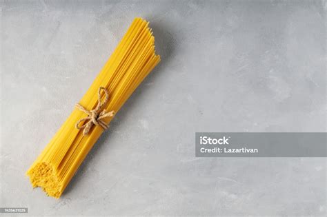 회색 배경에 꼬기로 묶인 생 스파게티 콘크리트에 노란색 익히지 않은 파스타 스파게티 평면도 복사 공간 건조한에 대한 스톡 사진 및 기타 이미지 Istock