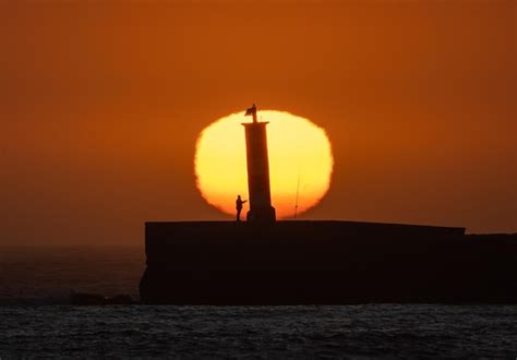 Premium Photo A Man Stands On A Lighthouse With A Sun Setting Behind Him