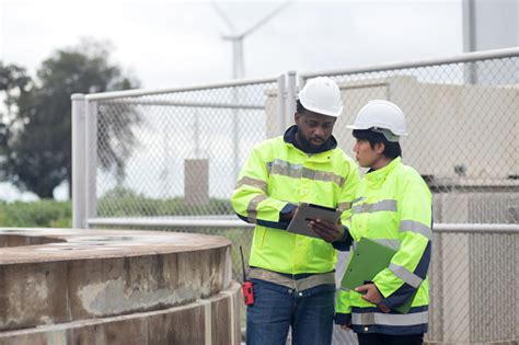 두 명의 엔지니어가 풍력 발전 단지의 풍력 터빈 지속 가능한 환경에서의 재생 가능 에너지 및 팀워크 문서 및 태블릿을 통한 전기 검사 산업 및 에코를 점검하고 검사합니다 2