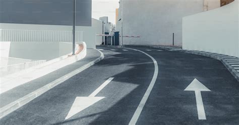 도로 표시와 양쪽의 작은 보도 뒤에 셀룰러 안테나 화창한 날로 반대 화살표가있는 끝의 장벽을 따르는 좁은 2 차선 아스팔트 도로의 수직보기 사진 Unsplash의