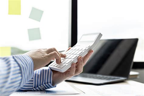 여성 감사원은 백인 계산기를 누르고 그녀는 민간 기업 감사자이며 고위 경영진에게 제출하기 전에 회사 재무 제표의 수를 검토하고