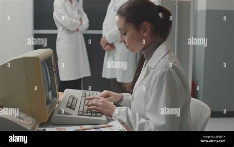 Woman Working With An Old Retro Computer In A Laboratory Data Analysis And IT Technology