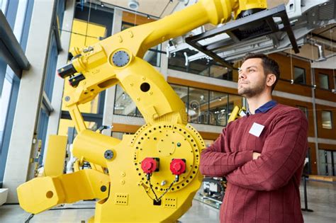 Engineer Overseeing Industrial Robot With Gripper Arm In Modern