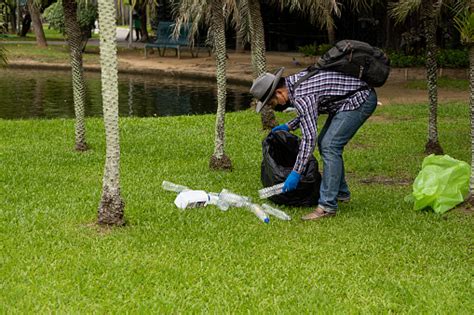 자원봉사자들은 공공 공원 주변의 쓰레기 봉투에 플라스틱 병을 수거합니다 환경 보호 및 글로벌 오염의 바닥 개념에 쓰레기를 수집