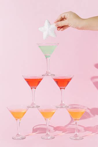 분홍색 배경에 별과 여자의 손이 있는 크리스마스 트리 모양으로 배열된 화려한 칵테일 잔 새해 파티 또는 축하 최소한의 개념 초현실주의에 대한 스톡 사진 및 기타 이미지