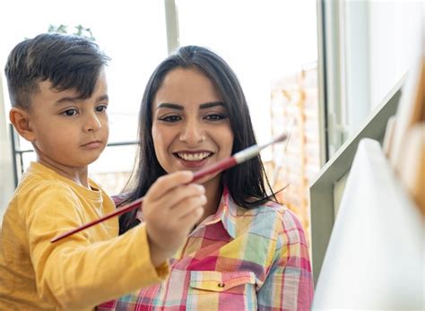 Premium Photo Latent Hispanic Mom Teaching Her Son How To Paint A