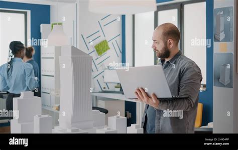 Man Holding Laptop To Work On Building Model Design And Blueprints Plan Architect Using