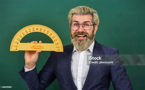 이것 보세요 대학 교육 개념입니다 수학 좋아하는 과목 기하학 수업을 공부하십시오 측정 개념입니다 양복을 입은 수염 난 남자 수학 교사는 각도기 도구를 사용합니다 학교로 돌아