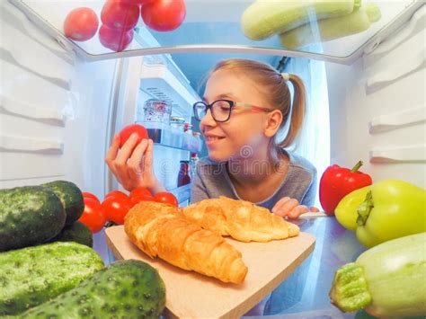 Портрет позиции девочки около открытого холодильника с здоровой пищи овощей и фруктов и