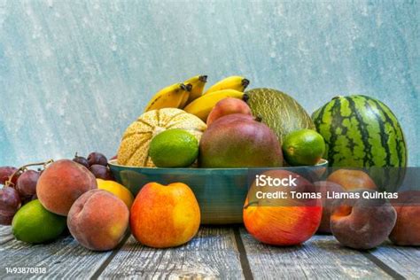 나무 테이블과 줄무늬 파란색 배경에 있는 모든 종류의 과일 복숭아 노란 바나나 잘 익은 수박 빨간 사과와 포도 라임 아프리카