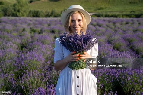 모자를 쓴 흰색 드레스 의상을 입은 여성 모델의 초상화 그녀는 라벤더 필드 사진 세션에서 서서 웃고 있습니다 어린 소녀가 라벤더 꽃다발을 들고 있습니다 행복과 자유 30