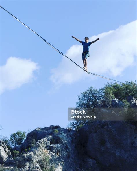 한 남자가 늘어선 새총을 따라 걷고 있었다 산에서 높은 라인 남자는 균형을 잡는다 자연에서 타이트 로프 워커의 성능 산의 배경에 하이 라이너 걷기에 대한 스톡 사진 및 기타