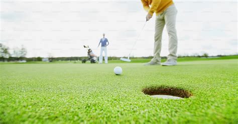 캐주얼 웨어를 입은 성숙한 남자가 녹색 필드에 서서 골프 공을 구멍에 넣으러 간다 사진 Unsplash의 골프 클럽 이미지