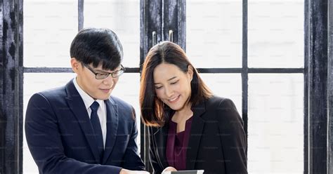 사업가와 사업가는 사무실에서 창문 근처에 서서 노트북을 함께 사용 사진 Unsplash의 태국 이미지