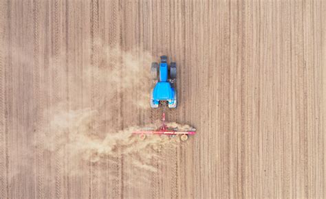 파란 트랙터 쟁기를 당겨 종자 파 종 트랙터를 만드는 흙 구름을 위한 토양을 준비 하는 공중 하향식 보기 계절에 대한 스톡 사진