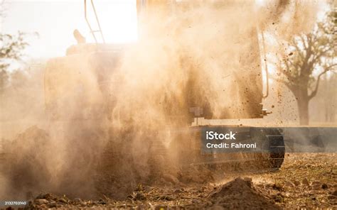 건설 현장에서 흙을 파서 작업하는 굴착기 공기 중에 먼지가 있는 철거 현장에서 작업하는 굴삭기 굴착 기계 지구 이동 기계 굴착