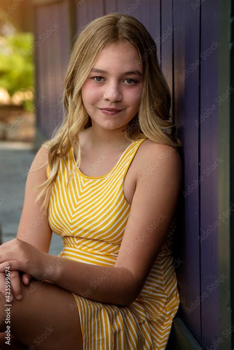 Vertical Outdoor Portrait Of A Beautiful Tween Girl With Long Blonde Hair Wearing A Yellow Dress