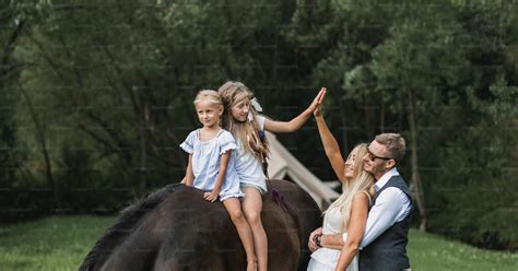 사랑하는 가족 아버지 어머니 그리고 야외에서 시골에서 말을 타고 있는 두 어린 딸 젊은 행복한 가족은 재미있게 놀고 서로에게 하이파이브를 주고 가족 시간 개념