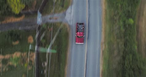 Young Friends Driving Old Red Truck On Summer Road Trip Together By
