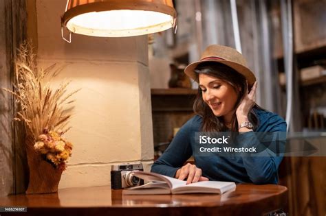 카페에서 모자를 쓰고 사진 카메라를 들고 테이블에 앉아 책을 읽는 예쁜 관광객 가냘픈에 대한 스톡 사진 및 기타 이미지 가냘픈 가방 가죽 Istock