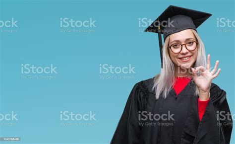 젊은 금발 여자 격리 된 배경 손과 손가락으로 Ok 사인을 하 고 긍정적인 미소를 통해 대학원 유니폼을 입고 성공적인 식입니다 교육에 대한 스톡 사진 및 기타 이미지