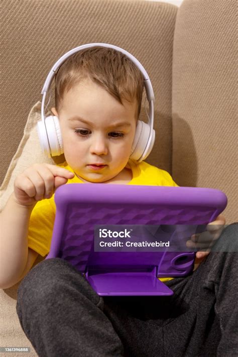 집에서 디지털 태블릿에서 게임을 하는 노란색 셔츠를 입은 작은 백인 소년 보라색 태블릿에 만화를보고 집에서 아이의 초상화 현대 의 아이 와 교육 기술 2 3 살에 대한 스톡
