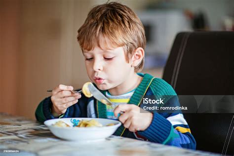 실내에서 파스타를 먹는 귀여운 작은 학교 소년 국내 부엌이나 학교 매점에서 금발 아이 귀여운 아이와 건강 식품 라비올리 또는 러시아 Pelmeni 가정 생활에 대한 스톡