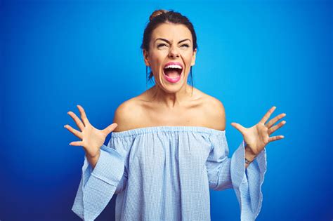 파란색 고립 된 배경에 롤빵 헤어 스타일을 입고 젊은 아름다운 여성은 미친 미친 소리와 공격적인 표정과 팔을 제기 고함 좌절 개념입니다 갈색 머리에 대한 스톡 사진 및 기타