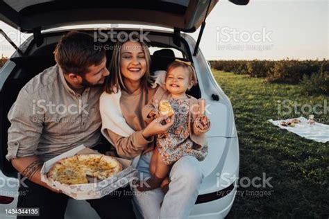 Suv 자동차 트렁크에 앉아 피자를 먹는 행복한 젊은 가족 엄마 아빠와 아기 딸이 주말 야외에서 즐거운 시간을 보내고 있다 차에 대한 스톡 사진 및 기타 이미지 Istock