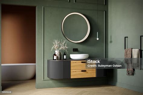 갈색 쪽모이 세공 마룻바닥 녹색과 주황색 벽 화장대 흰색 세면대 타원형 거울 욕조 내부 식물 전면 전망이 있는 현대적인 욕실 인테리어 현대적인 가구를 갖춘 미니멀한 욕실