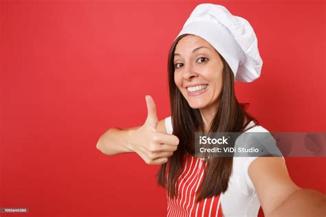 주부 여성 요리사 요리사 또는 줄무늬 앞치마 흰색 티셔츠 모자 요리사 모자 빨간 벽 배경에 고립 된 베이커 가 정부 여자 복용