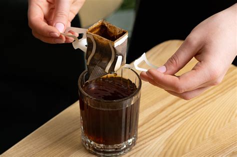 여성의 손은 유리 컵에 양조 된 드립 커피 한 봉지를 들고 있습니다 가방에 대한 스톡 사진 및 기타 이미지 가방 브루드 커피 구이 Istock