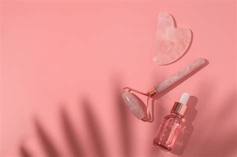 분홍색 배경에 화장품 액체 투명 젤의 석영 롤러와 핑크 유리 병을 마사지하십시오 공간을 복사합니다 드롭퍼 병 히알루론산 오일 세럼 얼굴 마사지와 휴식 과샤 건강관리와 의술에