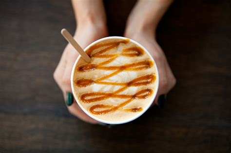 캐러멜 빅 커피 종이 컵에 우유를 들고 있는 여자들이 나무 테이블에 손을 얹습니다 카푸치노 또는 라떼 음료 테이블 플랫 평신도에