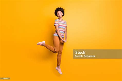 점프 높은 어두운 피부 물결 모양의 여자 보내기 Coquetish 공기 키스를 착용 캐주얼 여름 옷 고립 밝은 노란색 색상 배경의 전체 길이 프로필 사진 T 셔츠에 대한