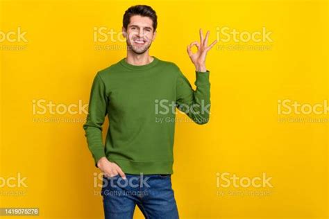 매력적인 귀여운 젊은 남자의 사진 녹색 스웨터를 입고 오키 기호 빈 공간 고립 된 노란색 배경 남자에 대한 스톡 사진 및 기타