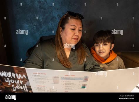 A Mother An Son Look At A Menu Together In A Restaurant To Choose What