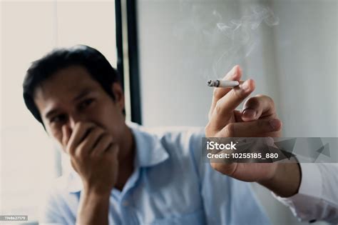 세계는 5 월에 담배 날 흡연을 중지 하 고 개념을 반대 하는 젊은 남자는 어두운 톤에서 담배를 들고 있는 사람들 가까이 앉아 연기의 질 식 개념에 대한 스톡 사진 및 기타