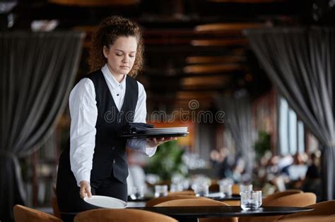 Young Woman As Female Server Setting Table In Restaurant Preparing For